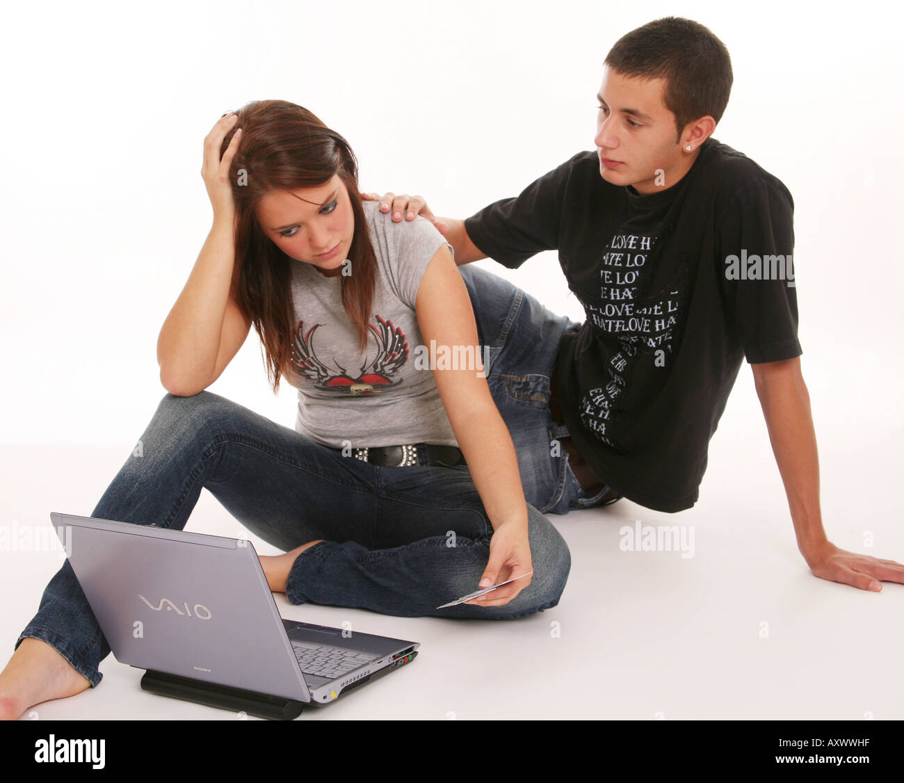 Boy Girl / Man Woman couple sat on floor looking at computer laptop ...