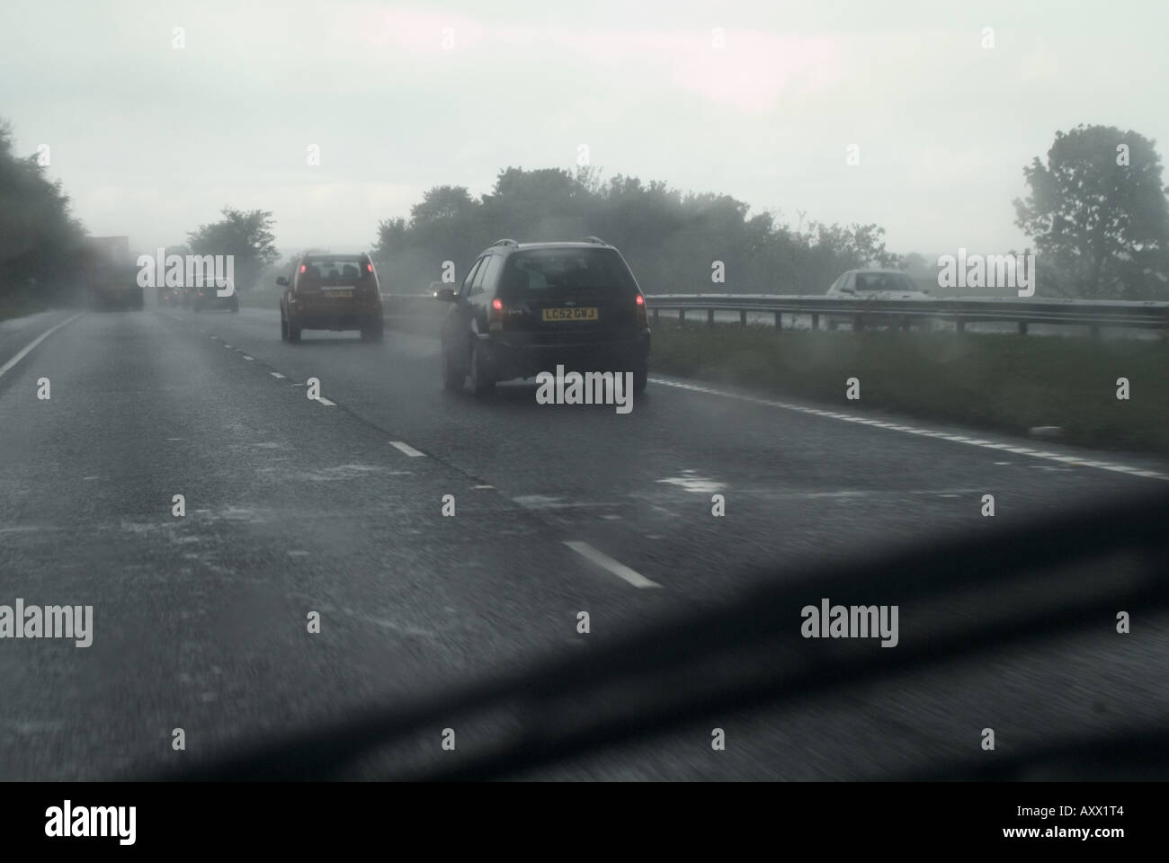 Drivers eye view of cars driving in the rain along a road in the UK ...