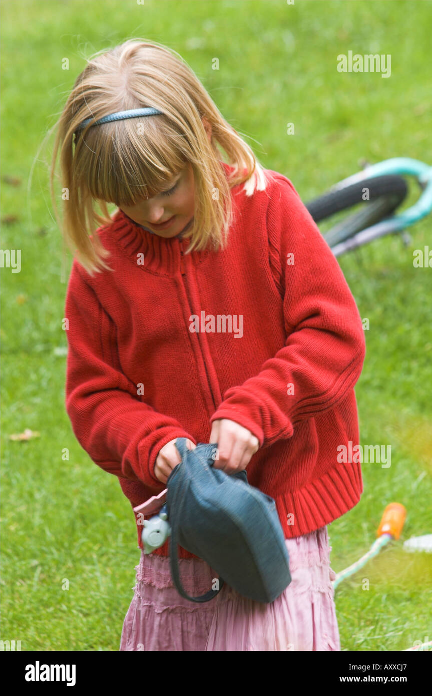young girl smiling cheekily warily with handbag Stock Photo - Alamy