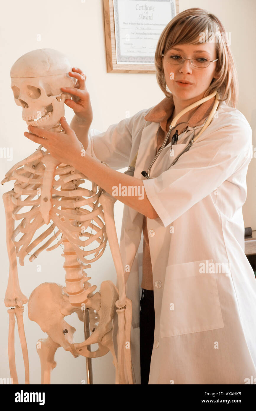 Female chiropractor uses a skeleton to teach a patient about the spine ...
