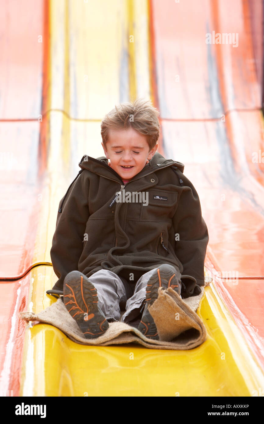 young boy at a fairground riding a large slide on mat Stock Photo - Alamy