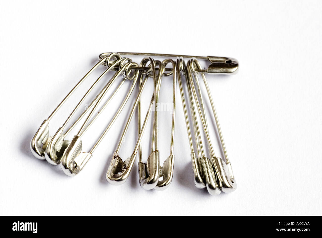Traditional silver safety pins attached together against a white ...
