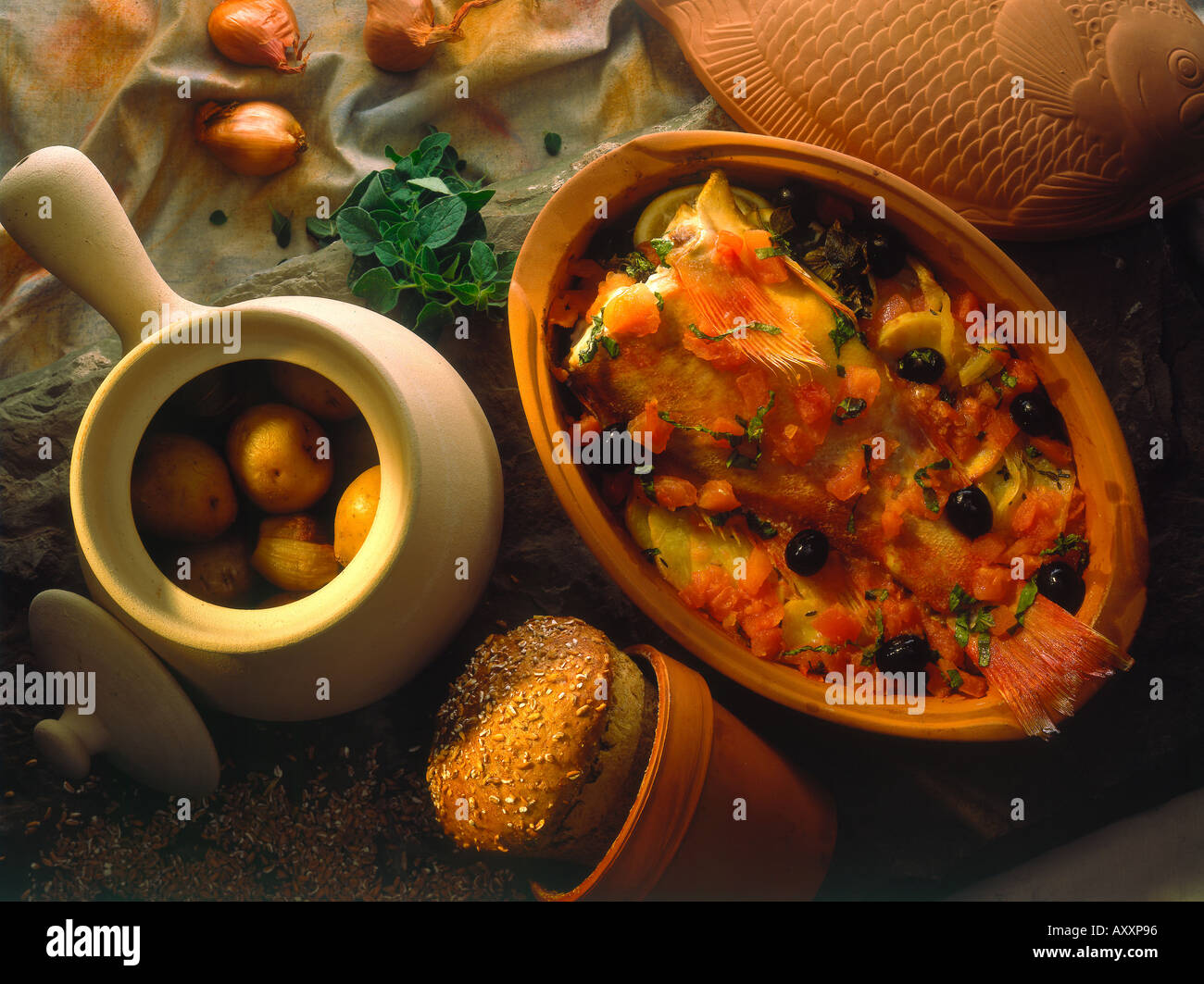 Baked Red Snapper Provencal with clay baked potatoes in terracotta dish ...