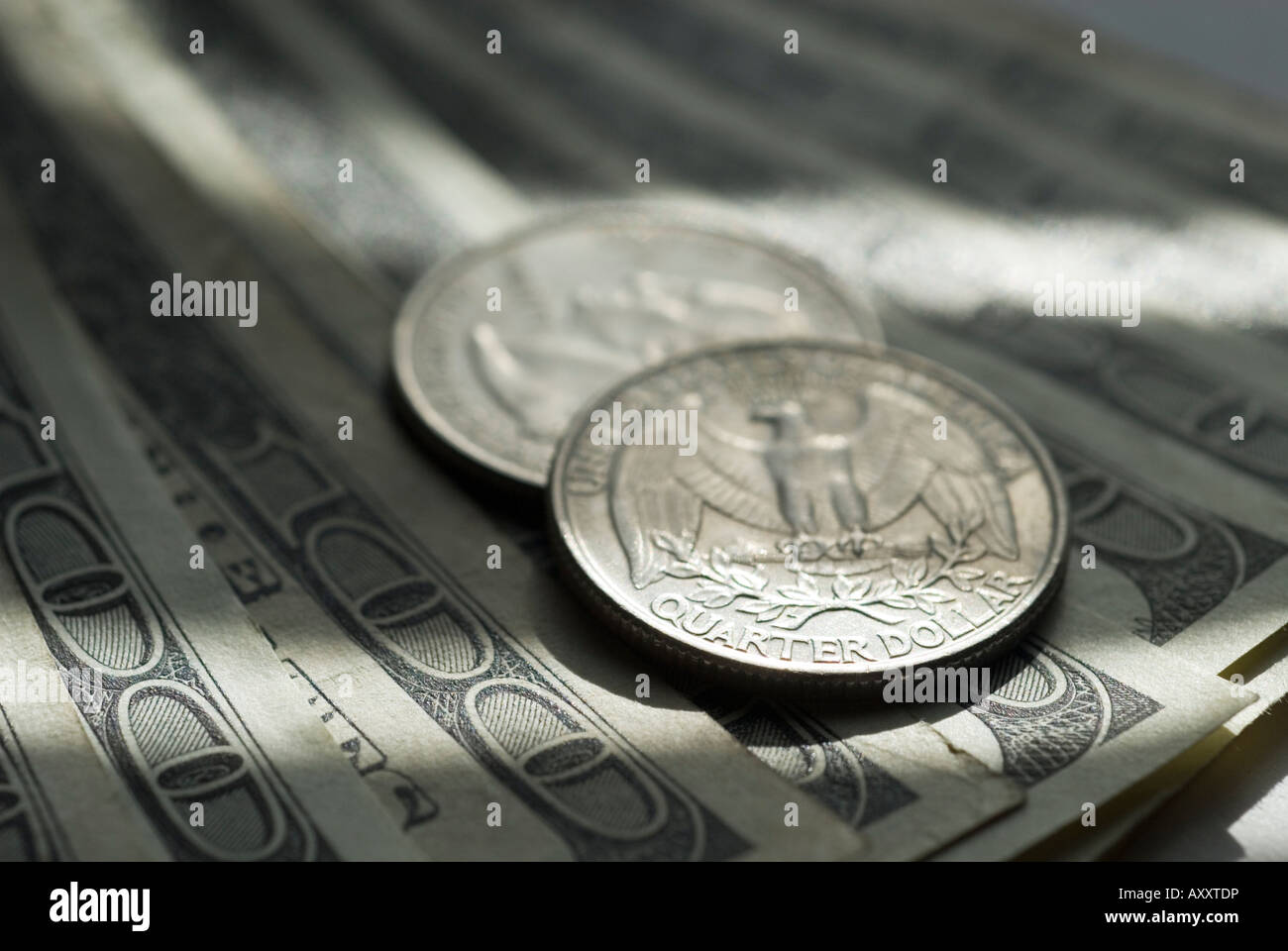 close up dollar notes and two quarter coins in dappled sunlight ...