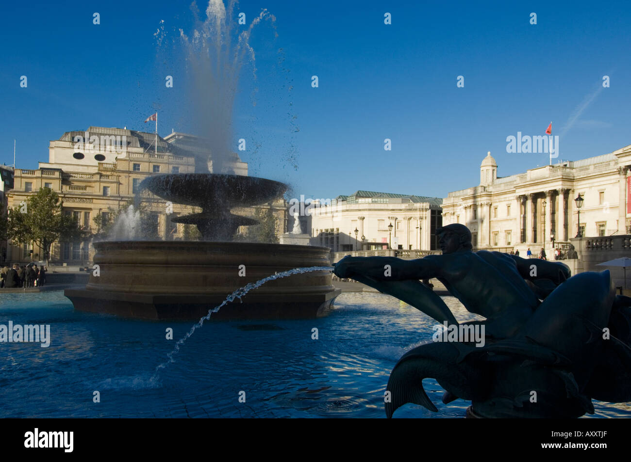 Water fountains in Trafalgar Square under a deep blue sky with the ...