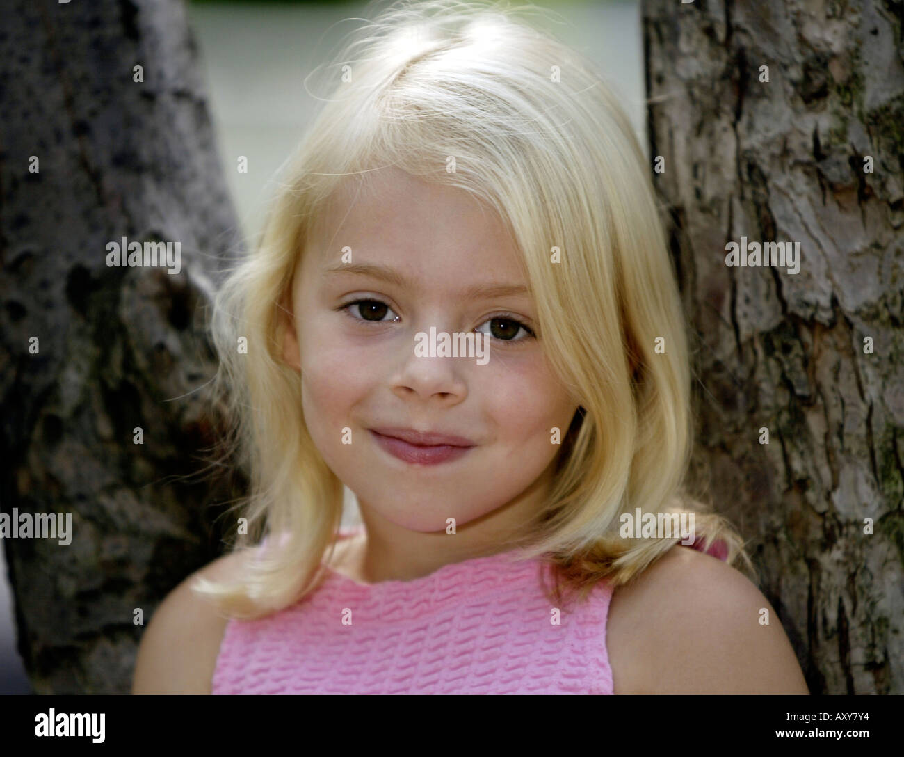 Five year old girl smiling between two trees Stock Photo - Alamy