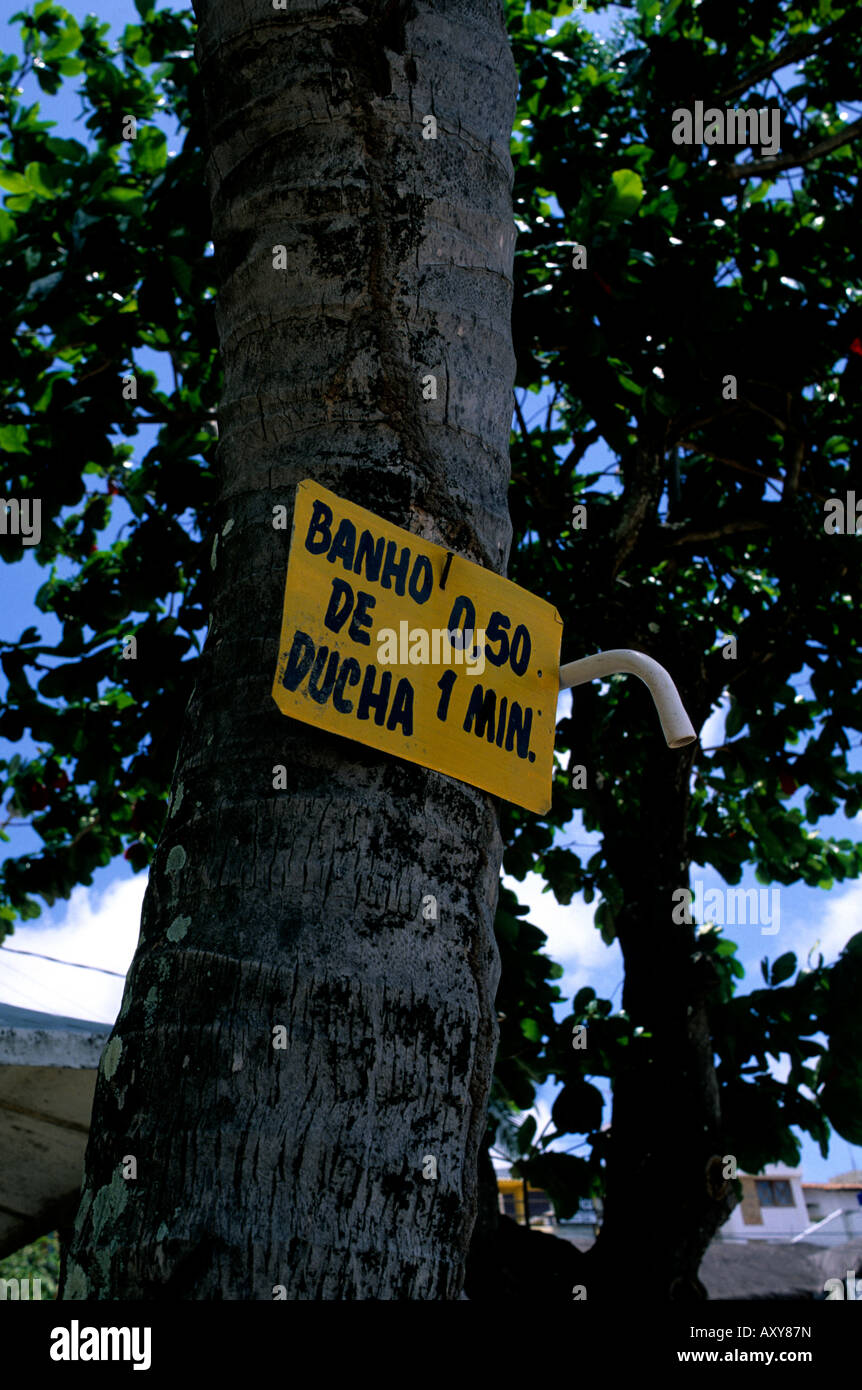 Simple beach shower with sign written in Portuguese fixed to a tree ...