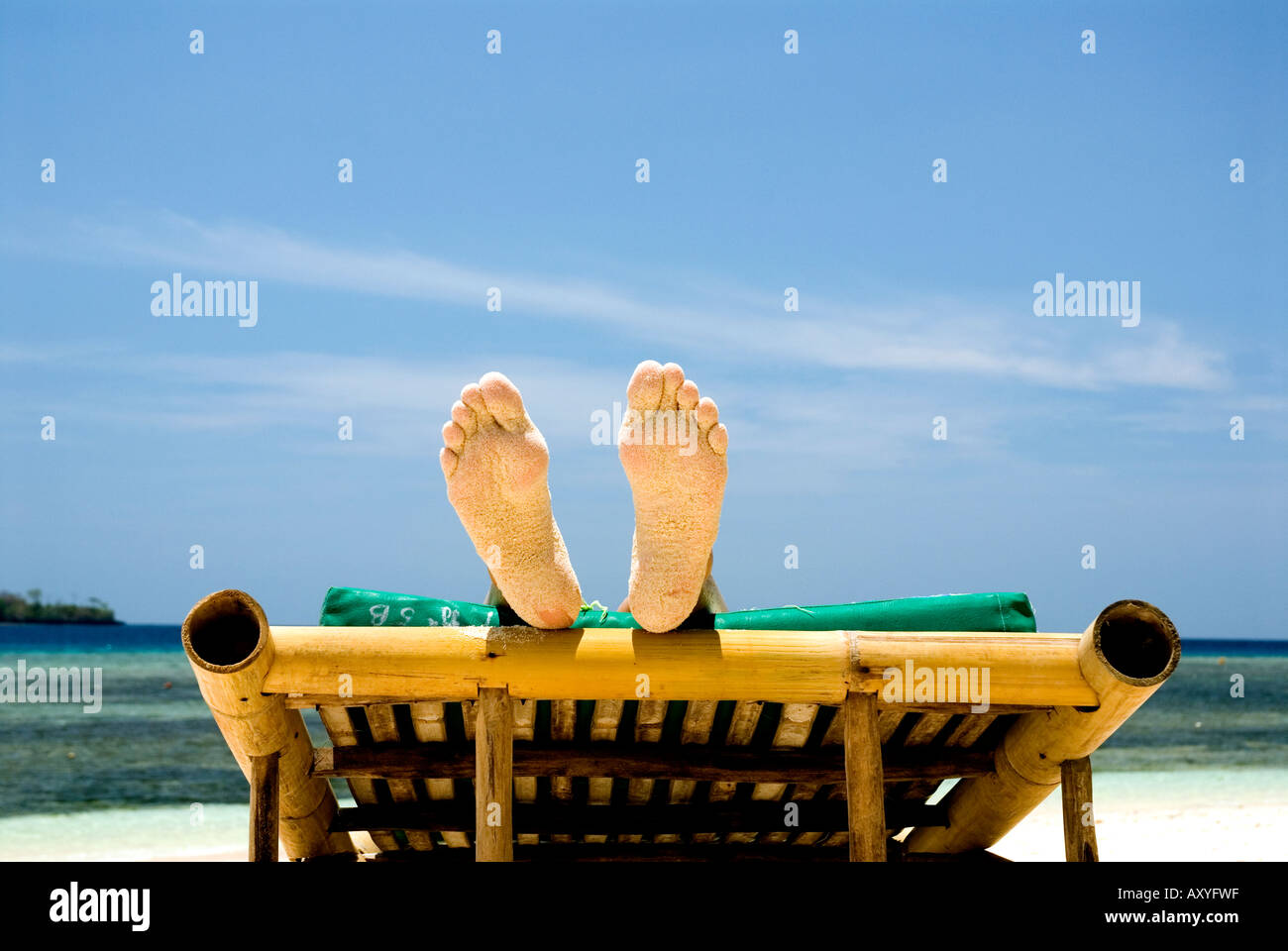 Two feet resting on bamboo lounger tropical beach holiday feet up put ...