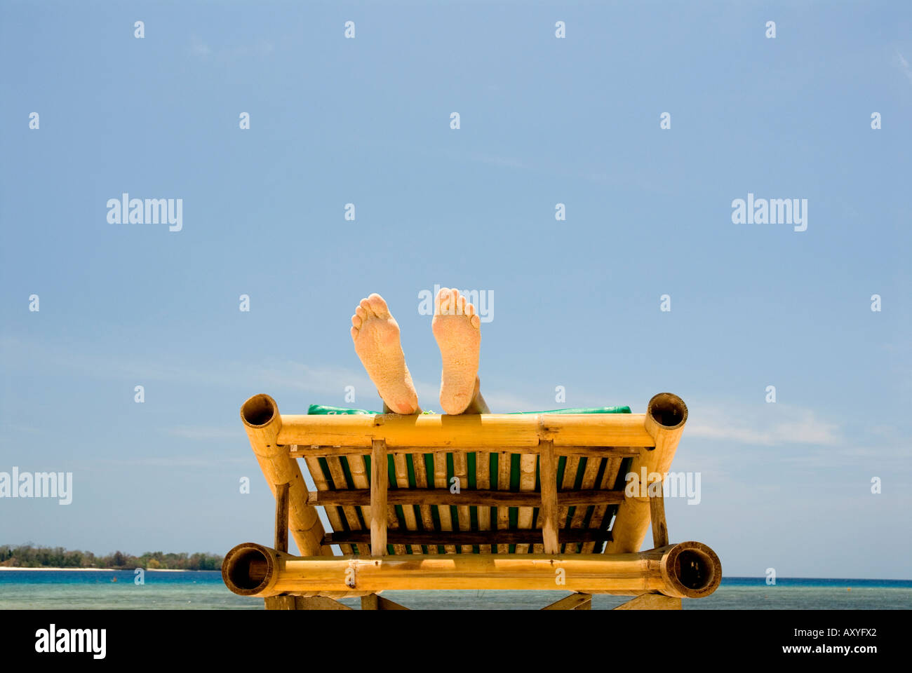 Two feet resting on bamboo lounger tropical beach holiday feet up put ...