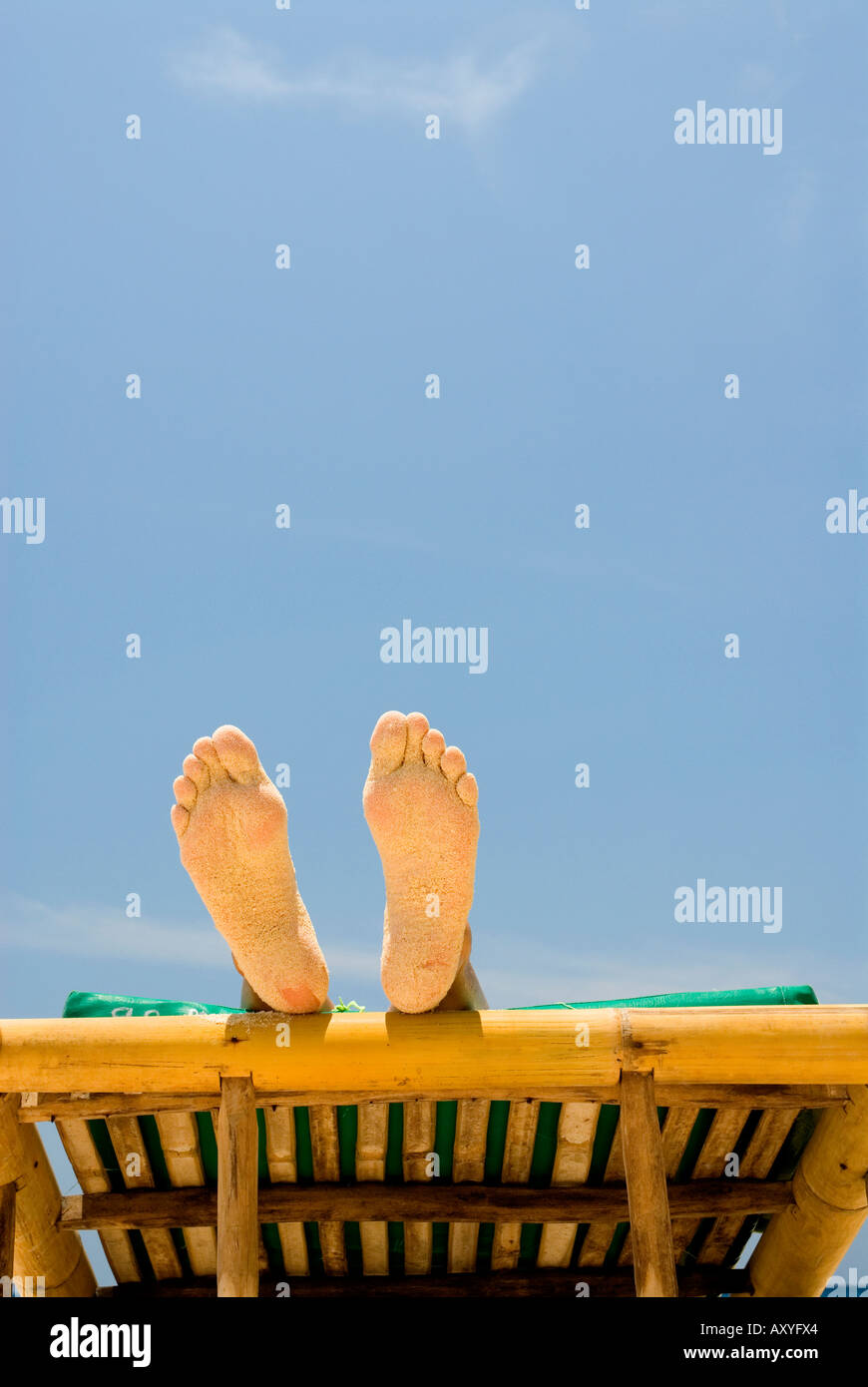 Two feet resting on bamboo lounger tropical beach holiday feet up put ...