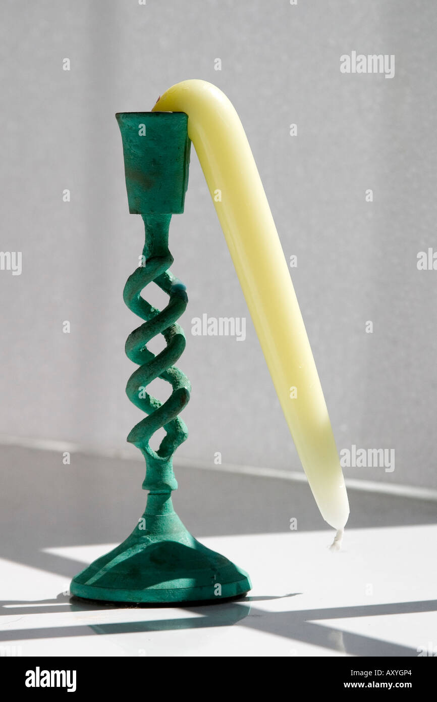 A drooping candle melted by the heat of the sun shining through a ...