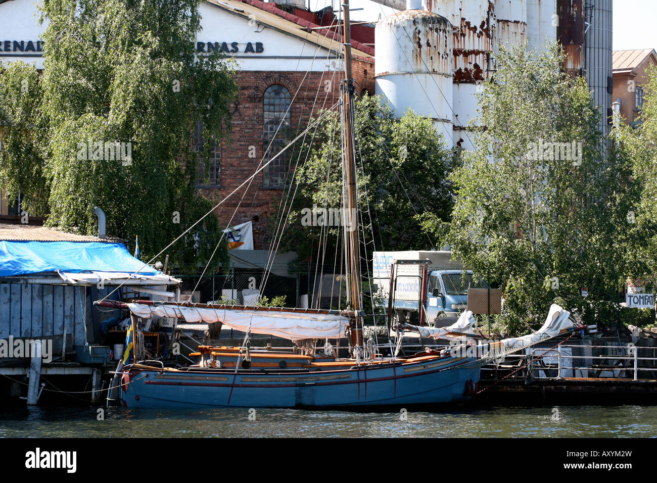 A sailing ship docked near trees and old buildings Stock Photo - Alamy