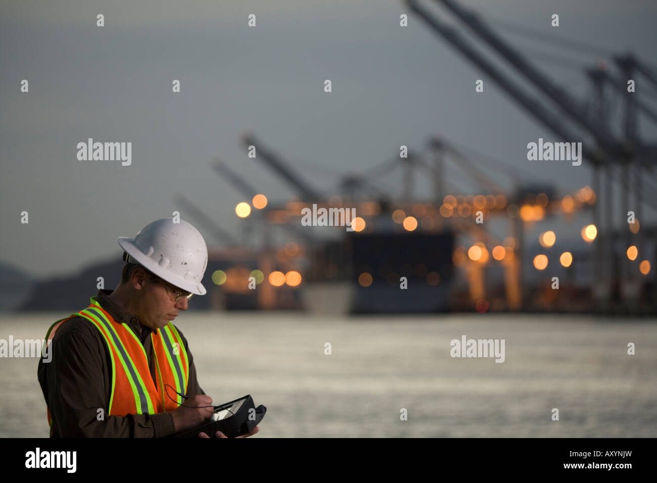 Worker with hard hat and safety vest holding tablet PC and writing on ...