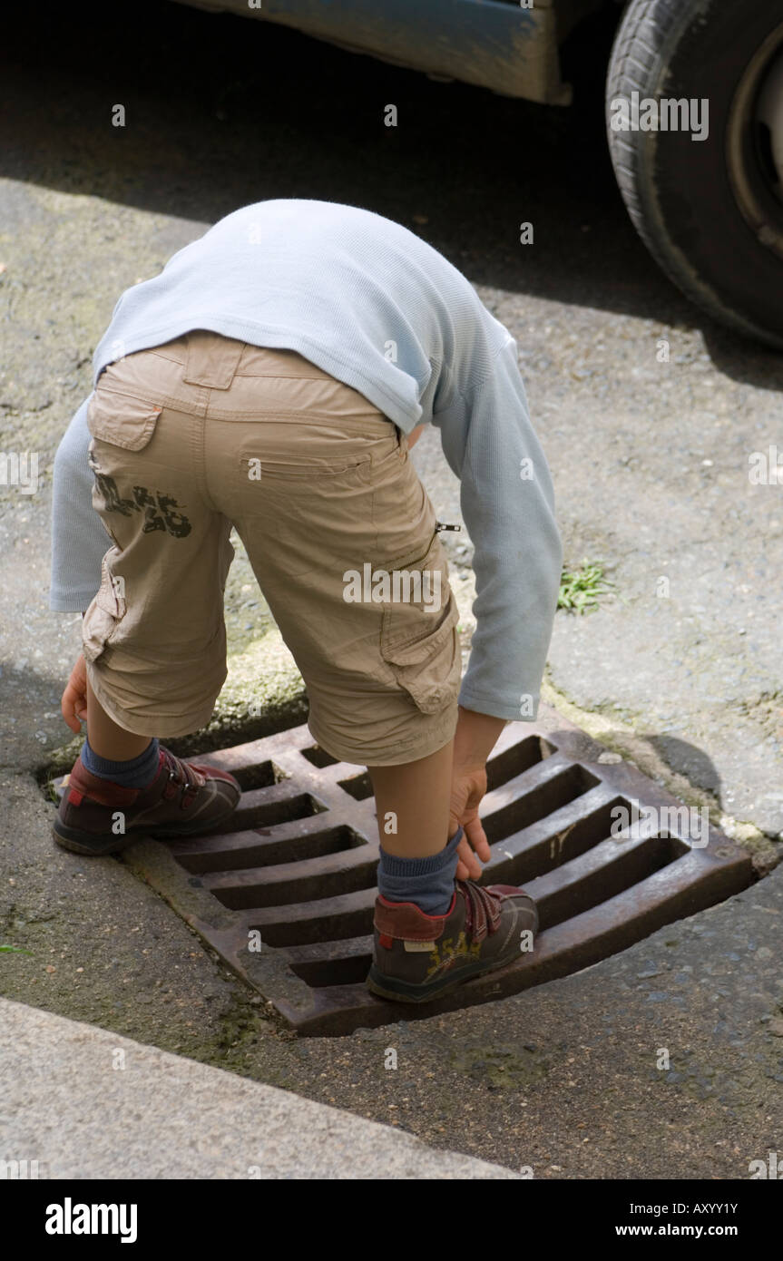 Boy Looking Down a Drain Stock Photo - Alamy