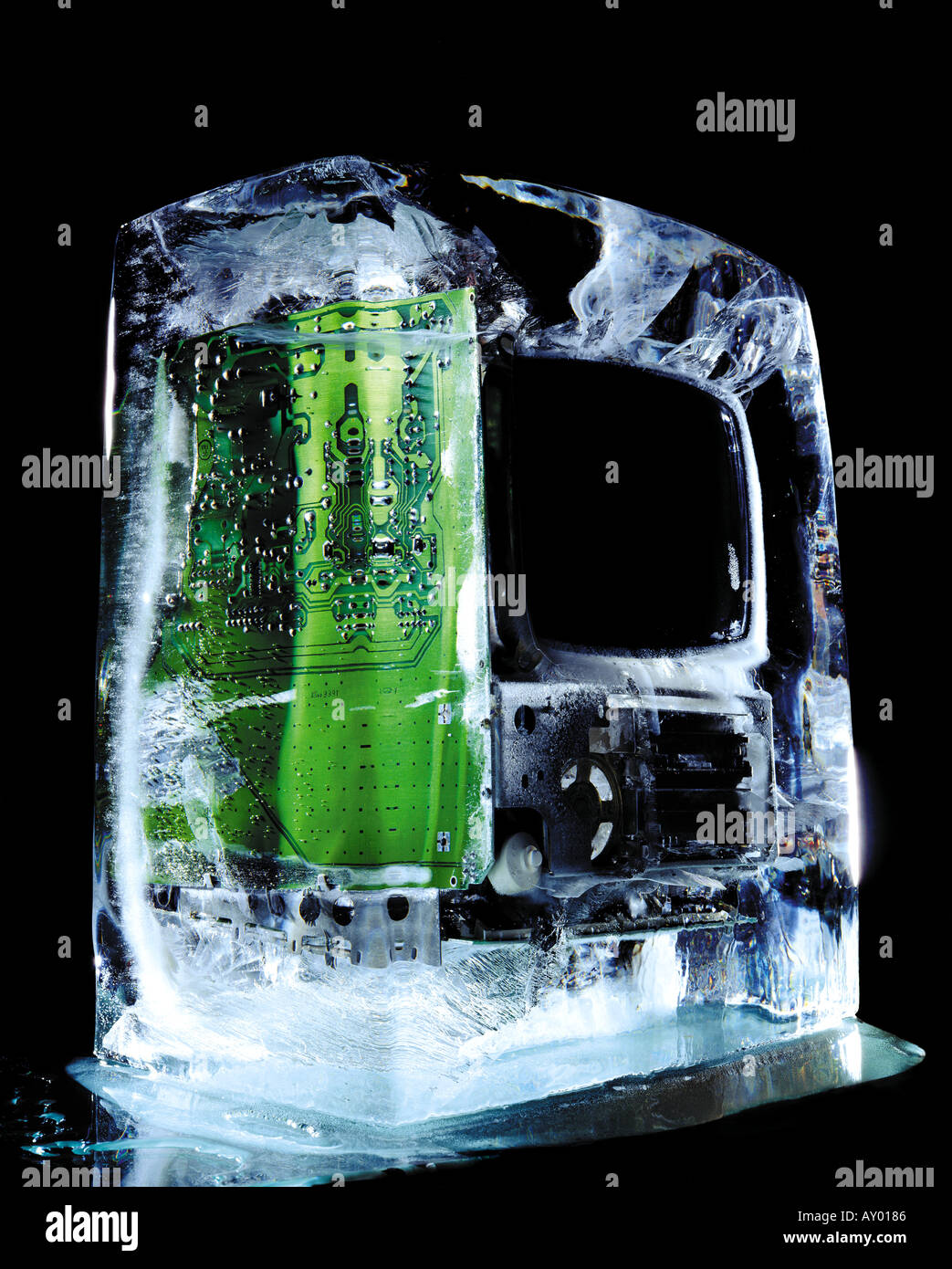 apple mac classic frozen into a lump of ice against a black back ground ...
