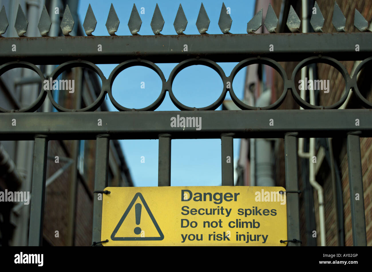 yellow sign with black text warns of security spikes at the top of a ...