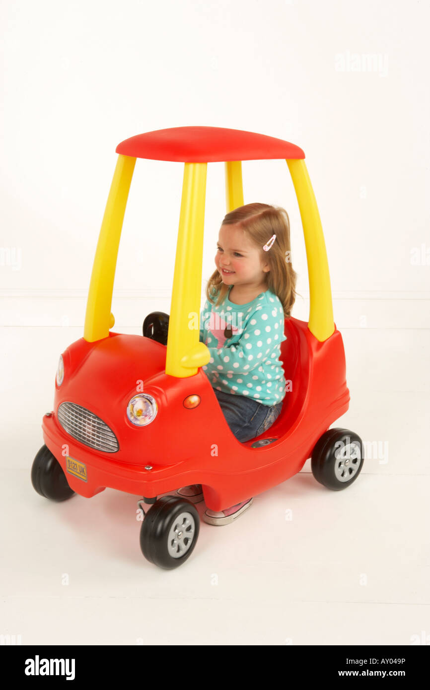 a girl drives a red toy car Stock Photo - Alamy