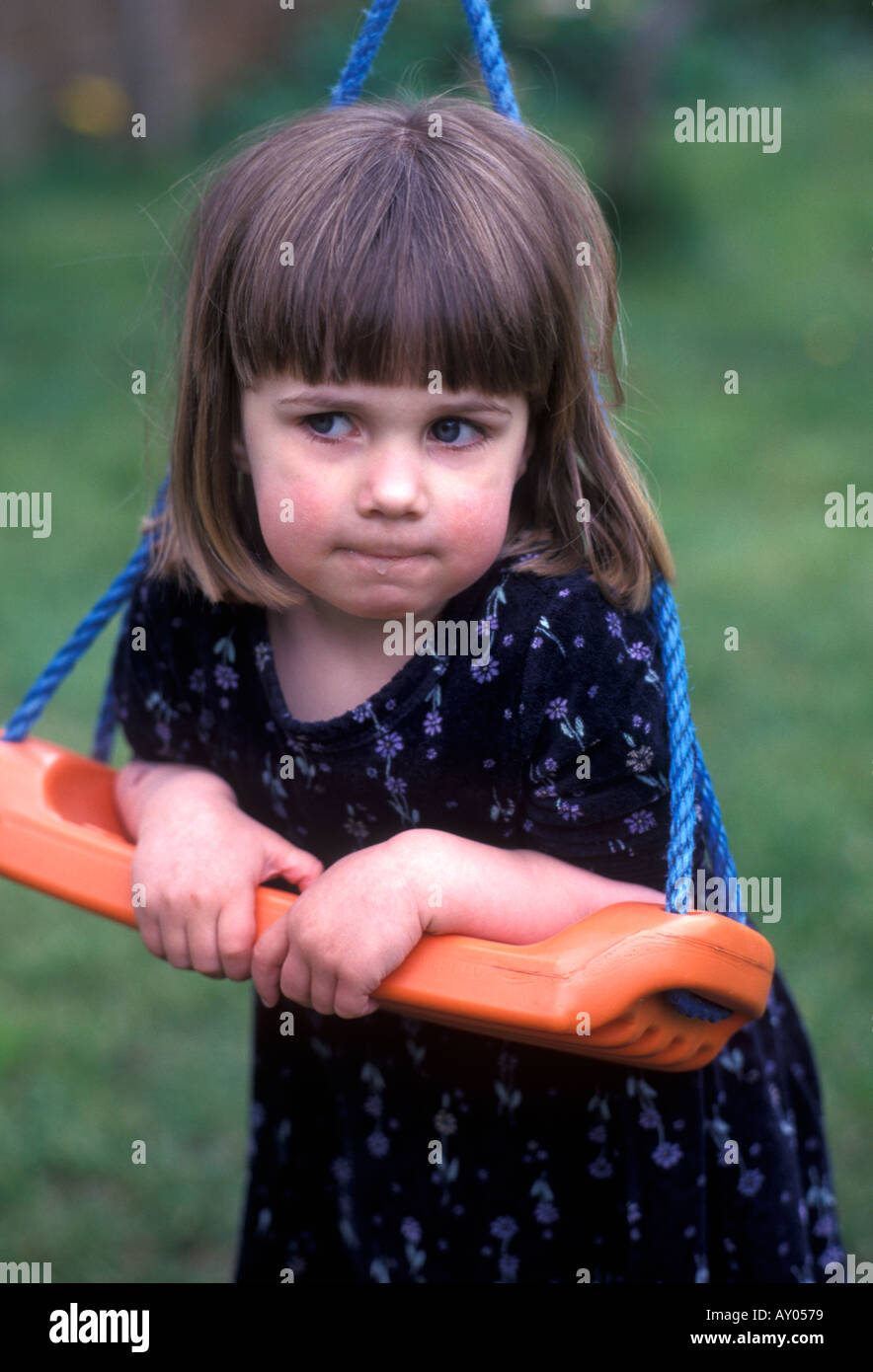 Small girl twisting swing seat Stock Photo - Alamy