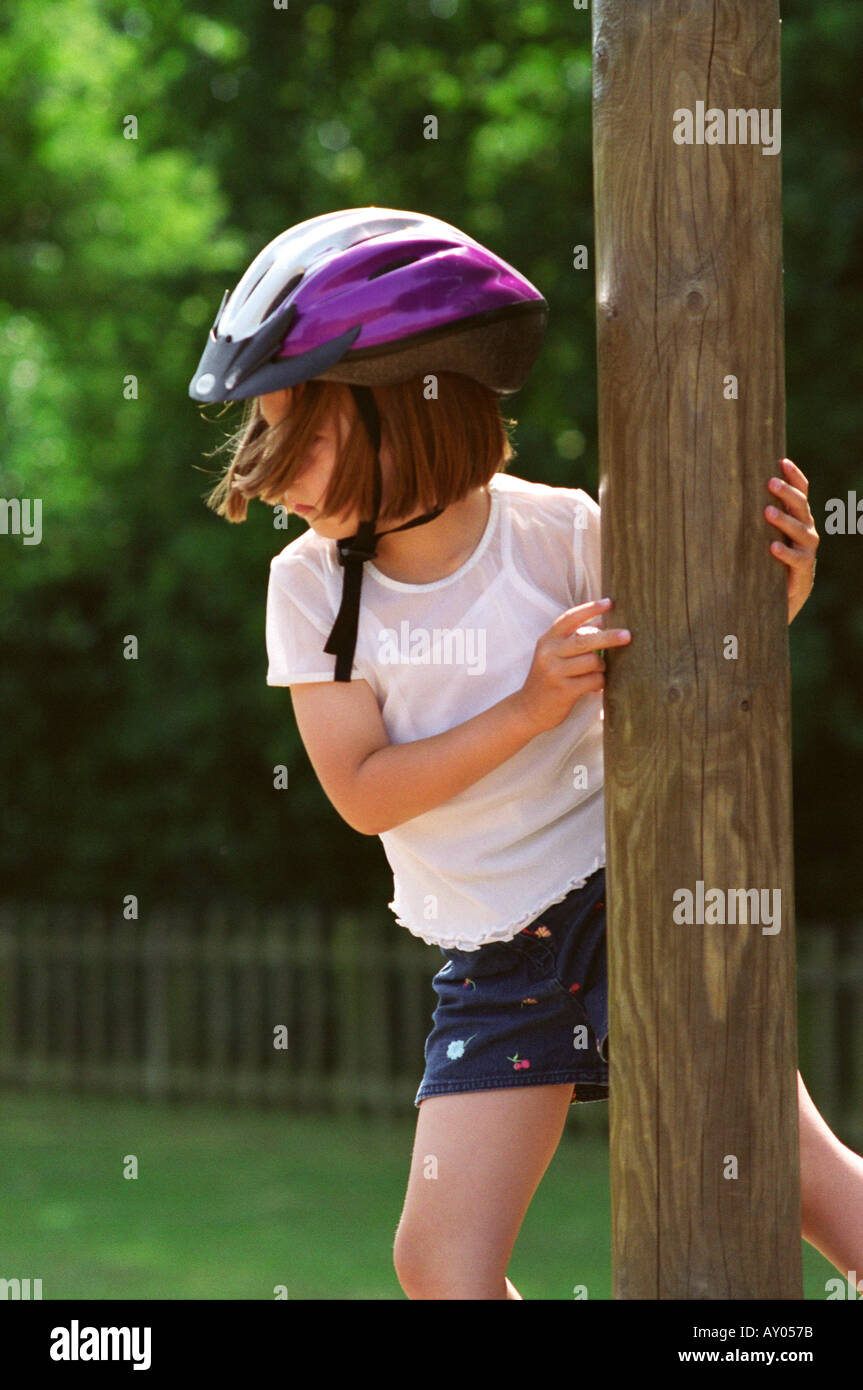 Girl with bike crash hat clinging to playground apparatus post Stock ...