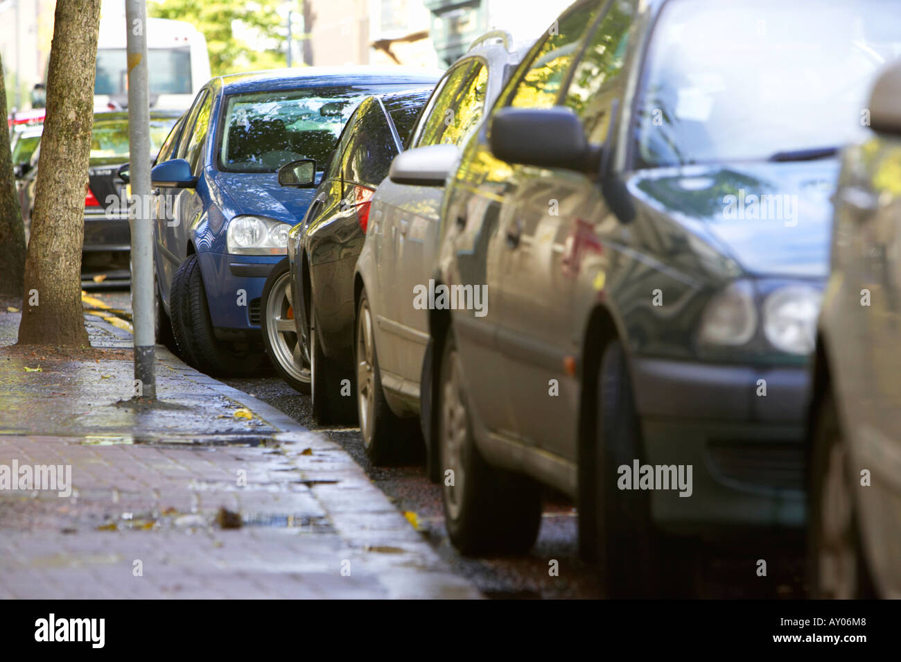 close up of side of cars on street parking next to the kerb on a side ...
