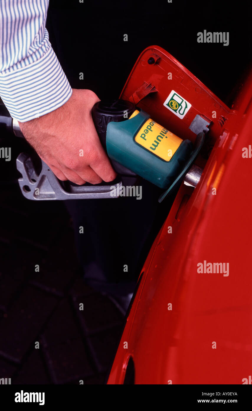 businessman filling up his red car with petrol at a petrol pump in the ...