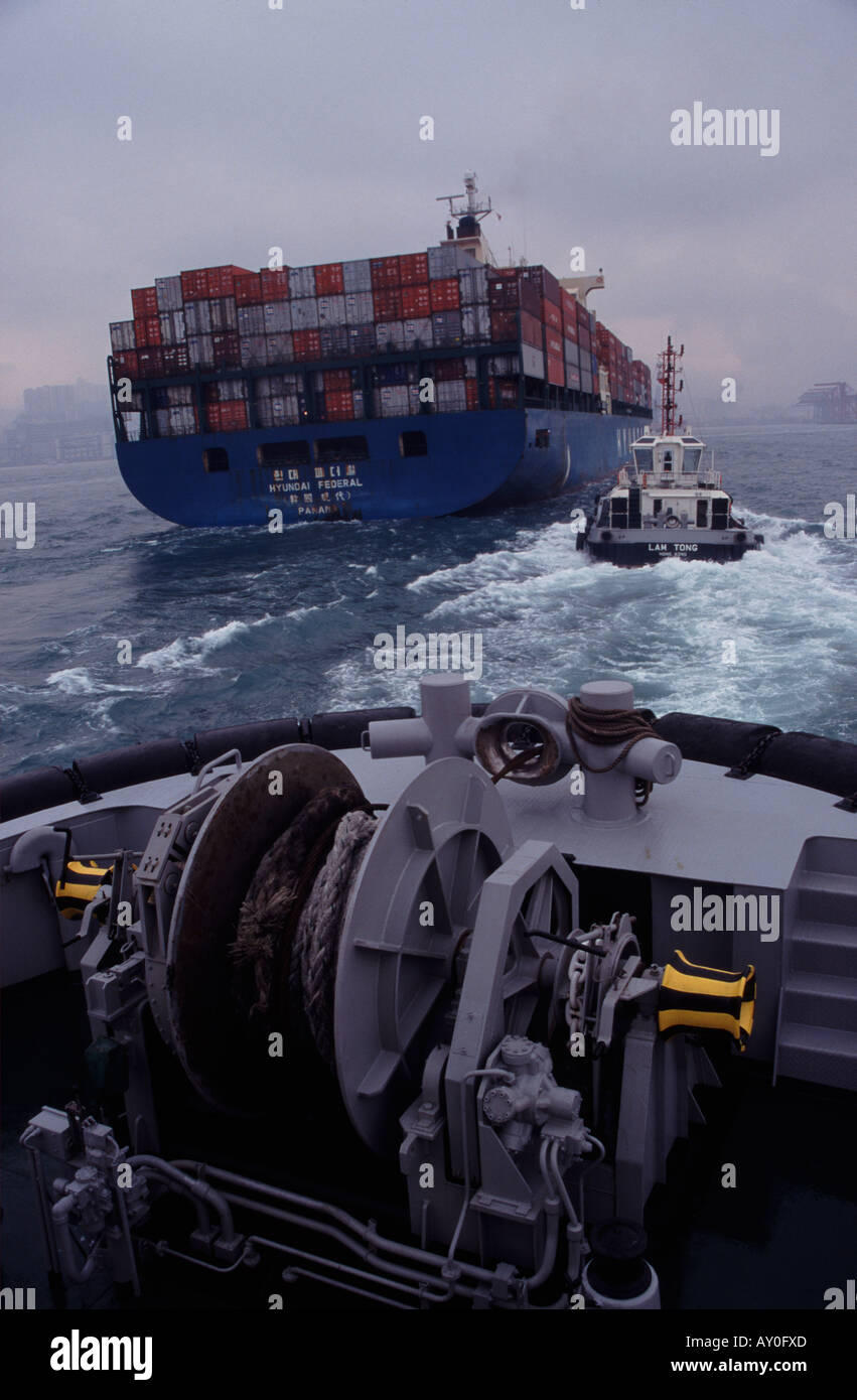 HUD tugboat in hong kong harbour behind huge container ship entering ...