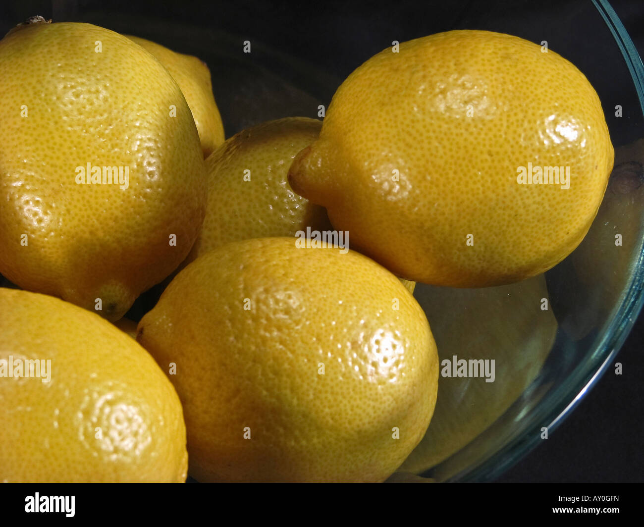 Whole yellow lemons in a glass bowl overhead nobody on black background ...