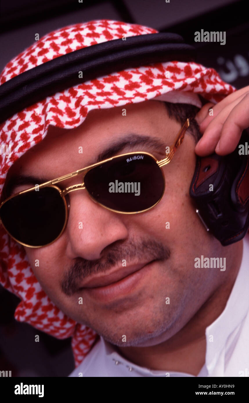 Arab on mobile phone wearing sunglasses looking at camera smiling ...