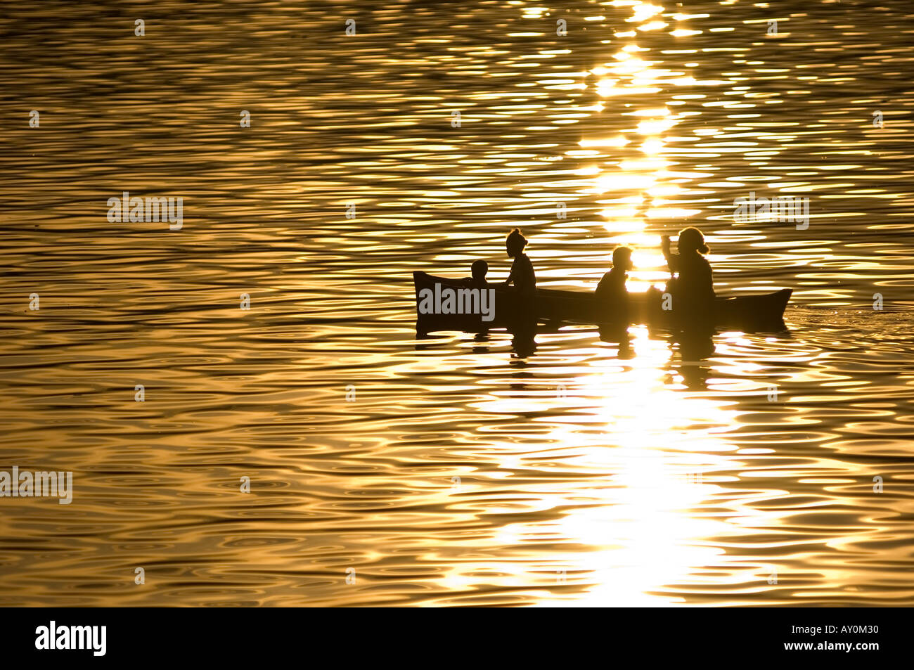 A family in a dugout canoe crossing a harbour at sunset, Manokwari ...