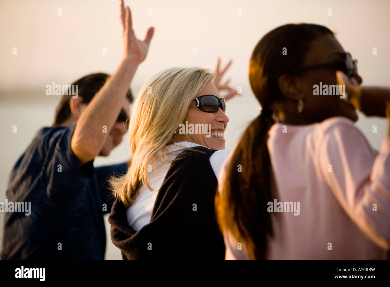 Cheerful friends waving while looking away Stock Photo - Alamy