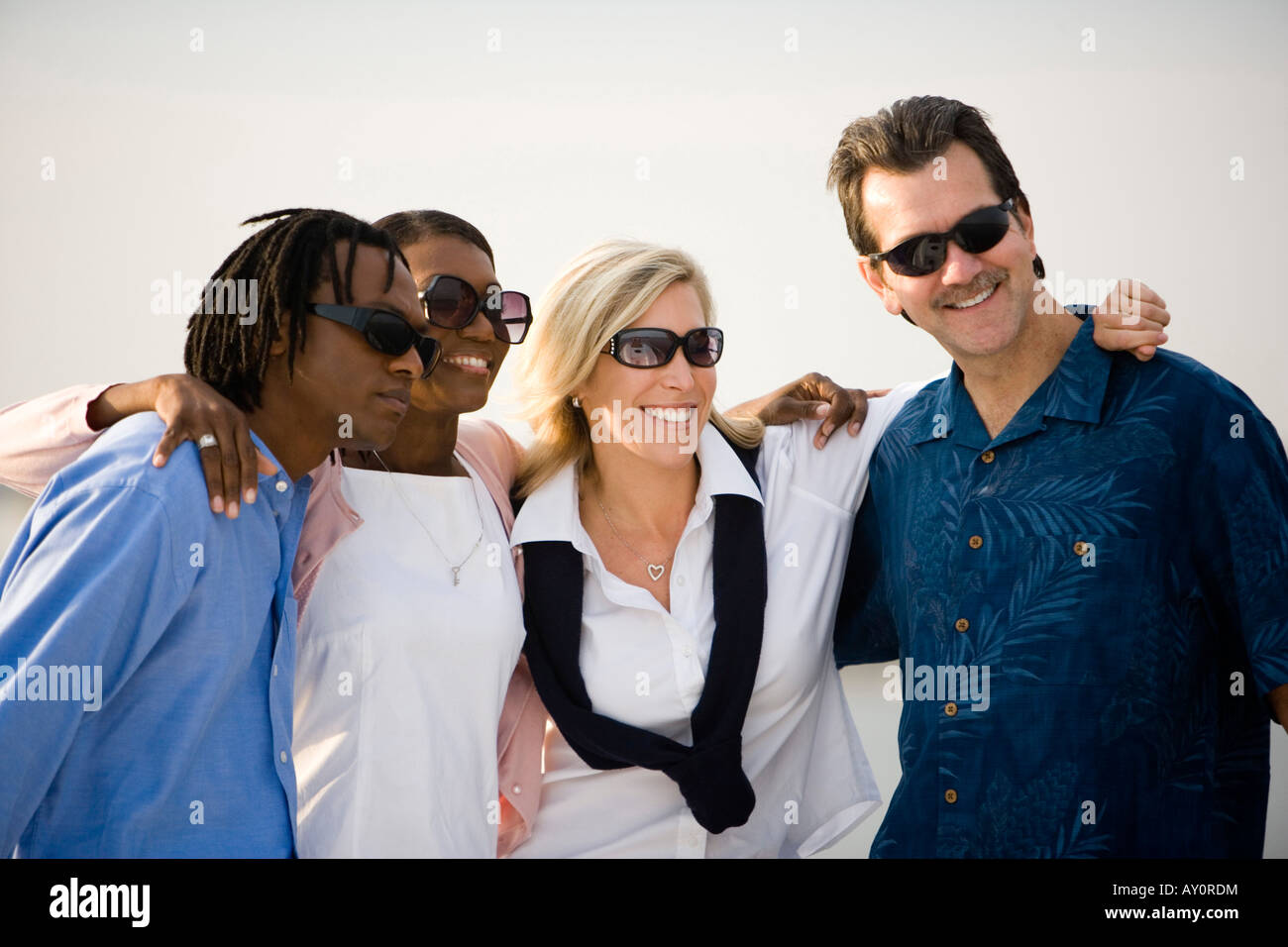 Smiling friends standing together with arm around Stock Photo - Alamy