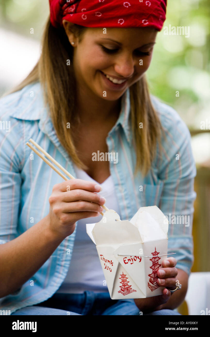 Cheerful young woman holding chopsticks and box Stock Photo - Alamy
