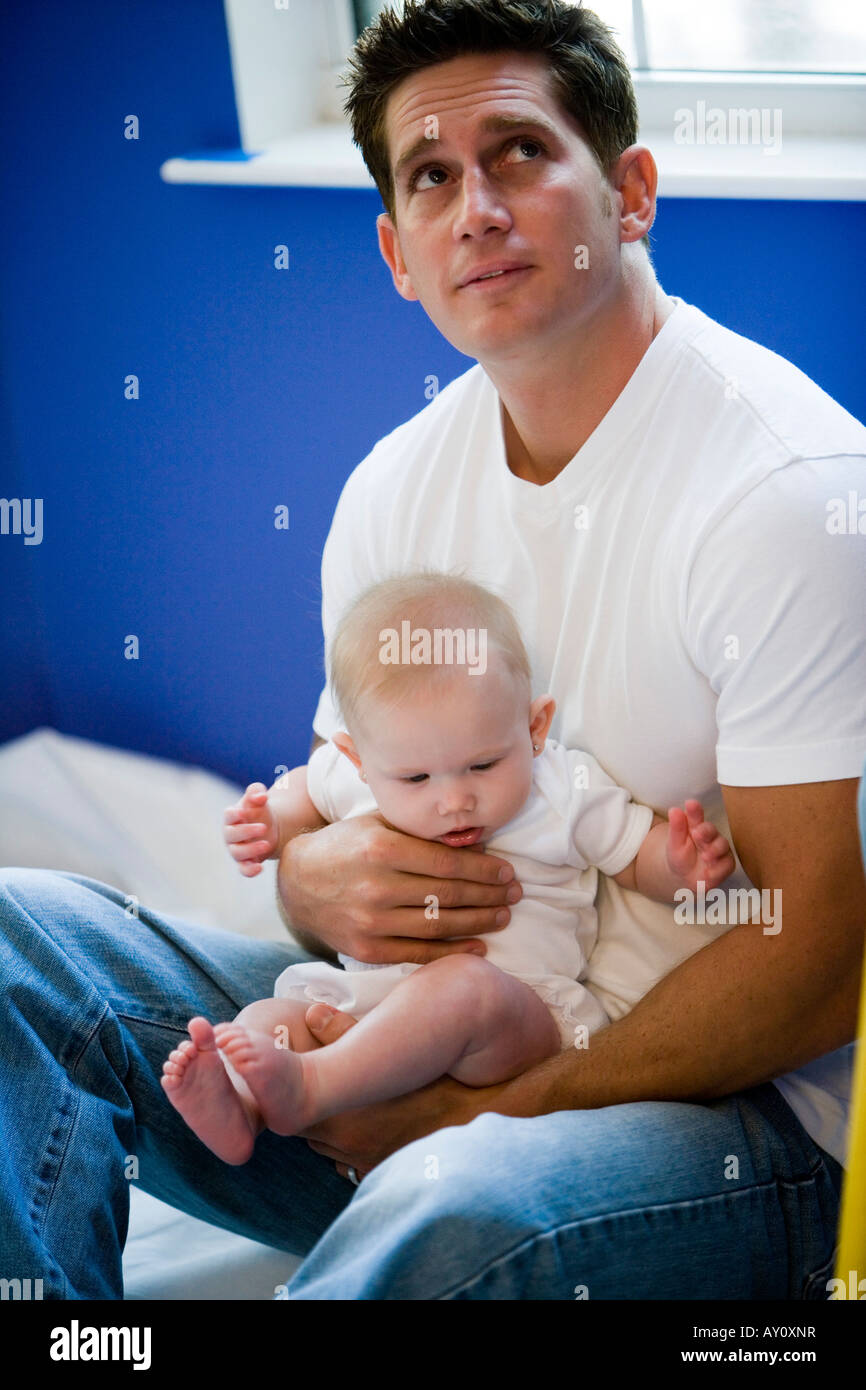 Young man holding baby and looking up Stock Photo - Alamy