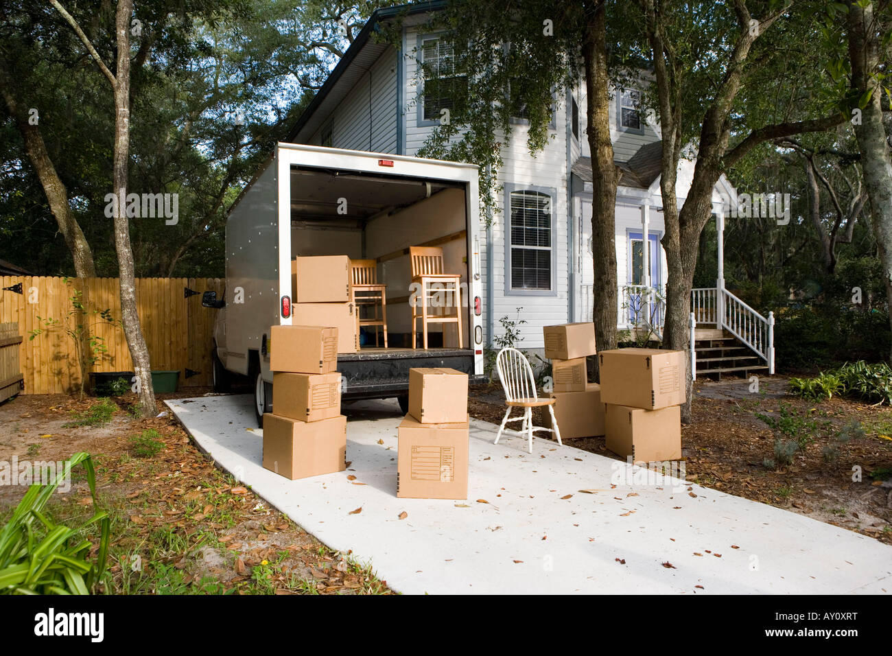 Moving van with cardboard box and chairs by house Stock Photo - Alamy
