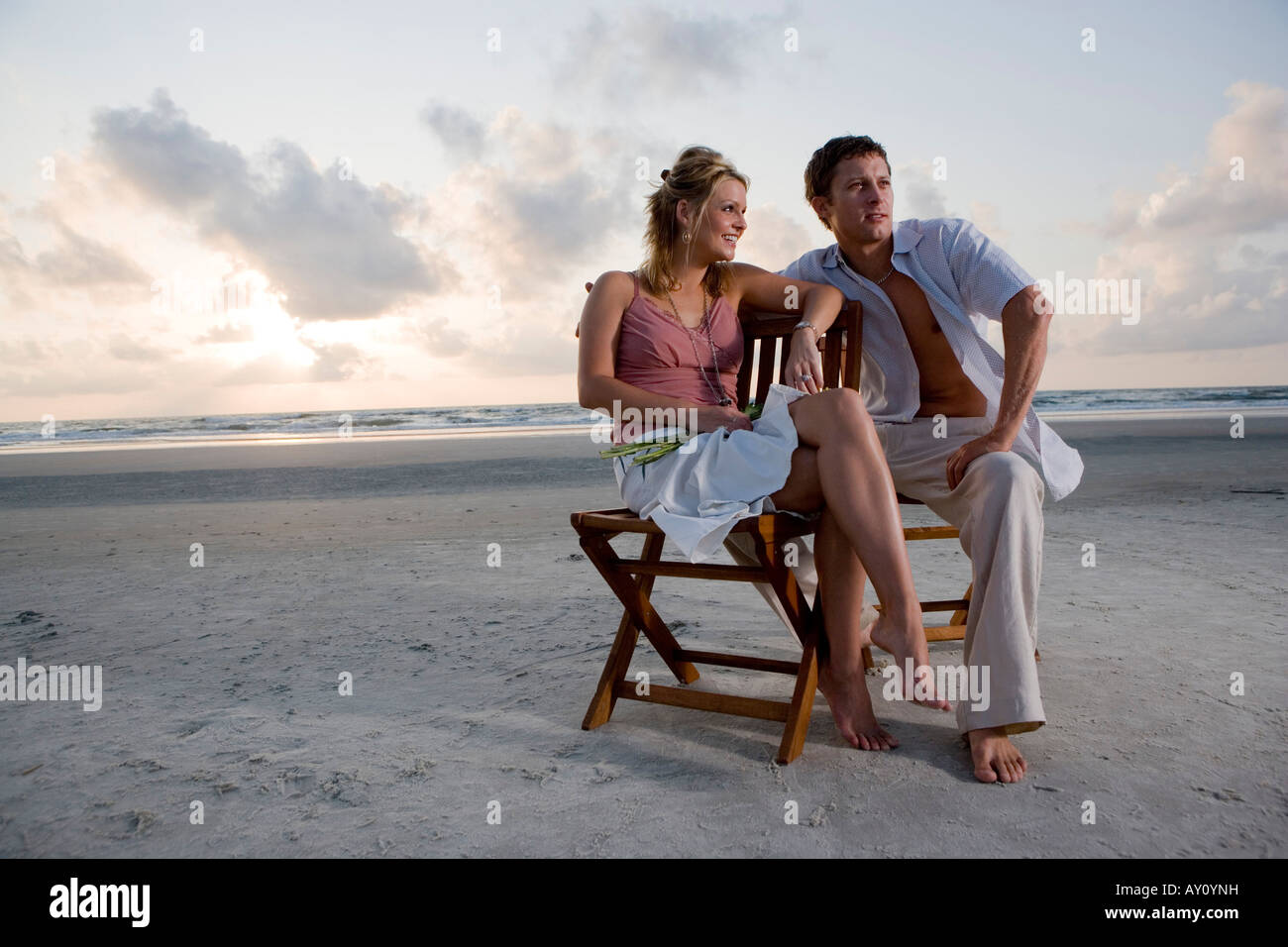 Young couple relaxing on chairs at the beach Stock Photo - Alamy