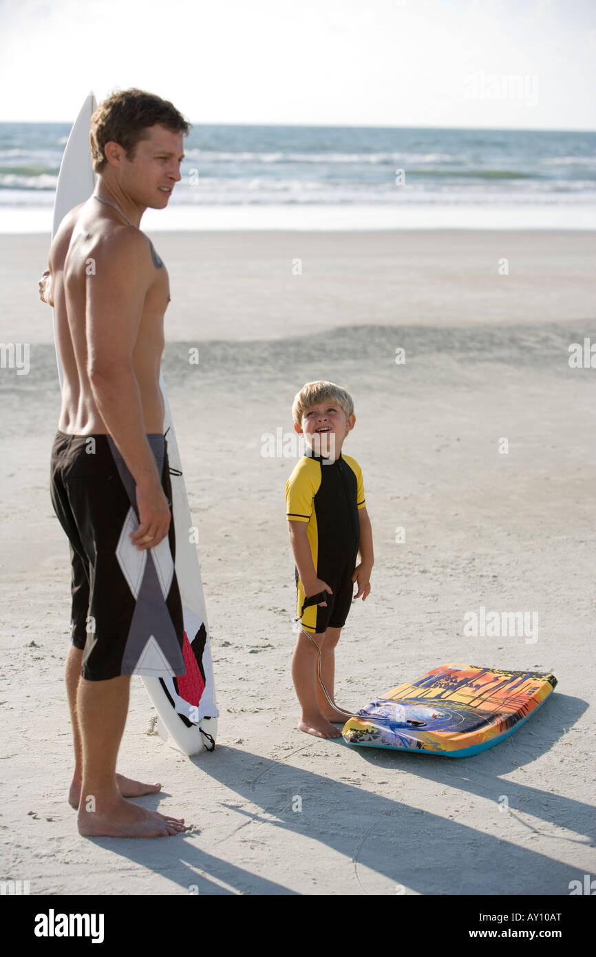 Father with his son standing by surfboard at the beach Stock Photo - Alamy