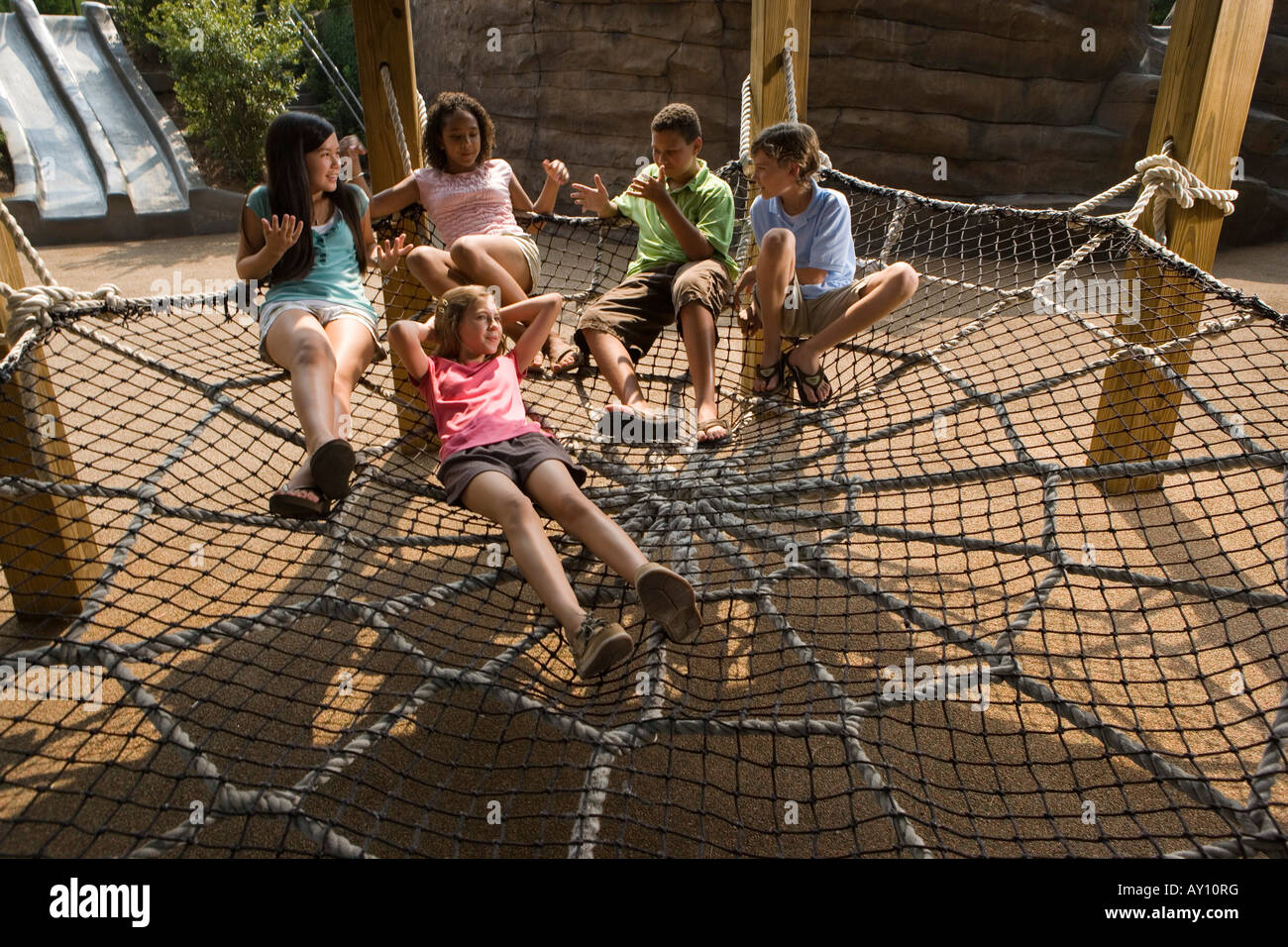 Teenagers sitting on net tied to the wooden columns Stock Photo - Alamy