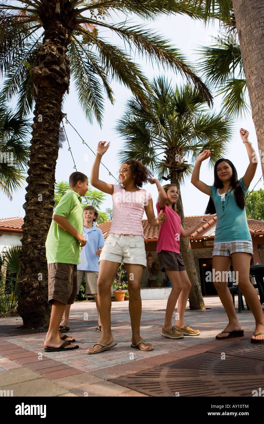 Teenagers dancing under a palm tree with a house in the background ...