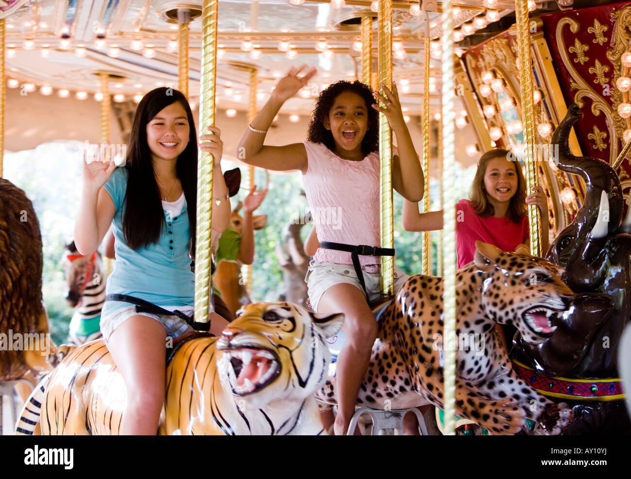 Cheerful teenage girls sitting on a carousel and waving hands Stock ...