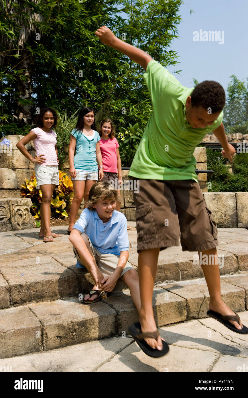 Teenage boy jumping over his friend with girls standing in the ...