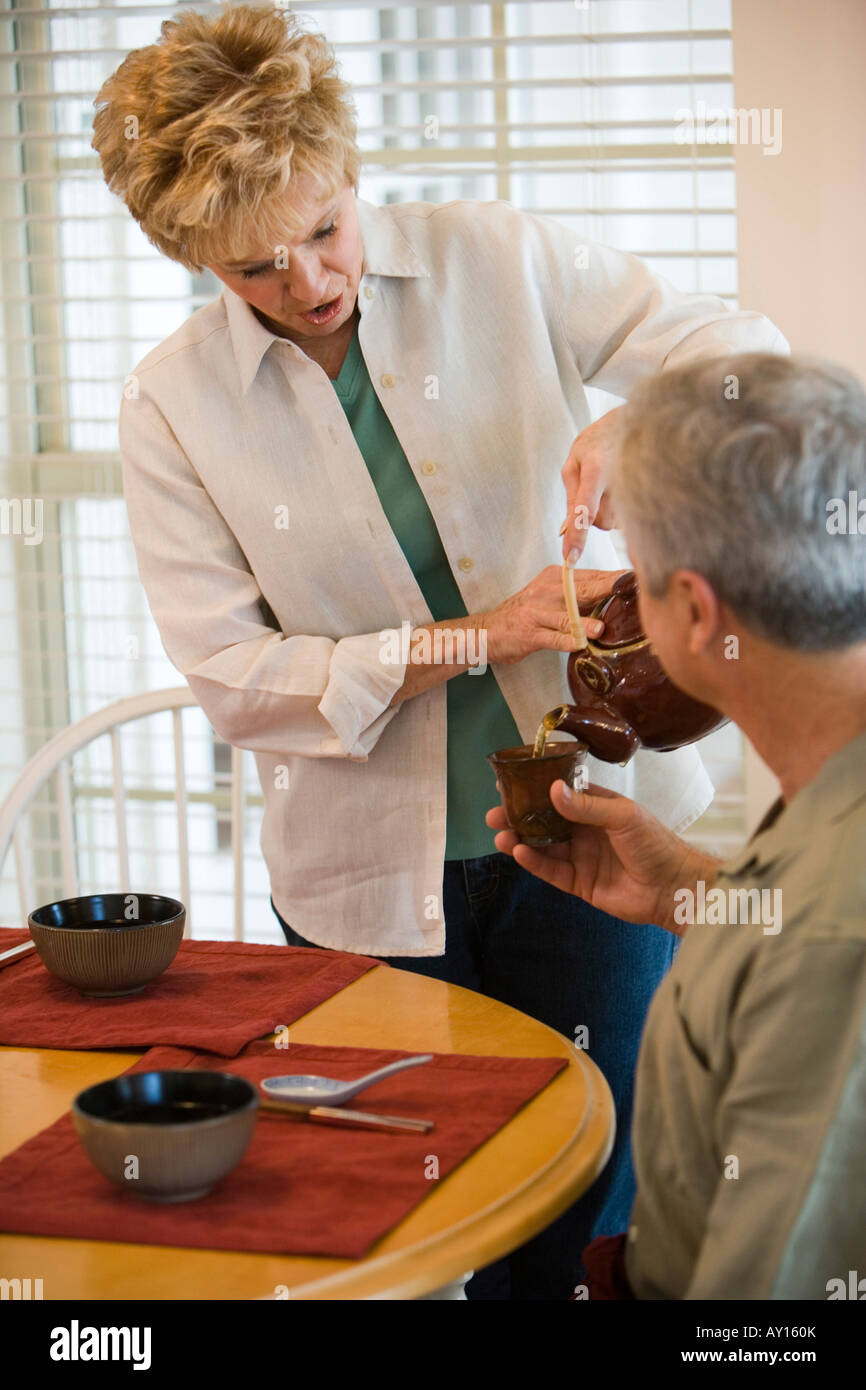 Mature woman serving tea to a man Stock Photo - Alamy