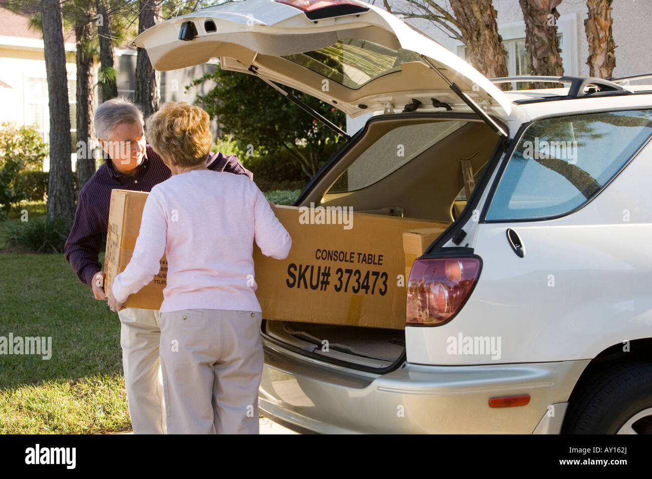 Mature couple removing a cardboard box from a car Stock Photo - Alamy