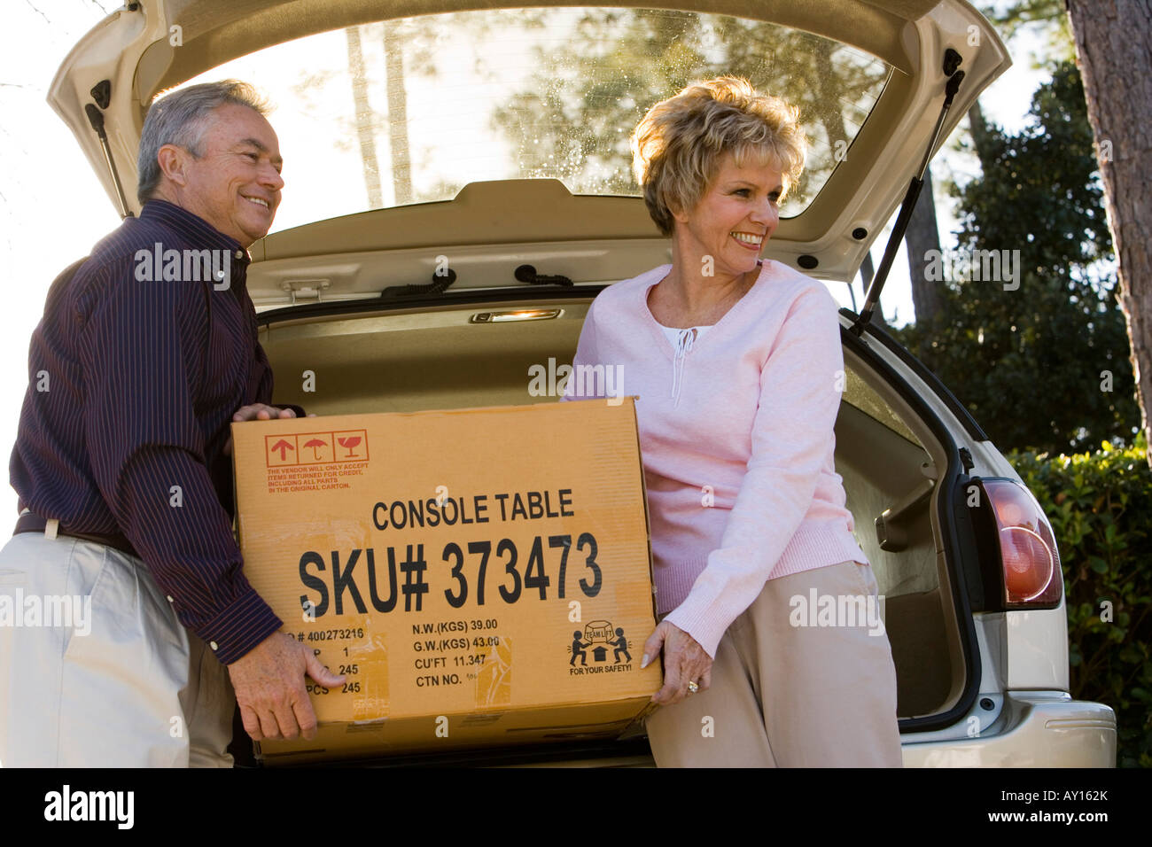Mature couple removing a cardboard box from a car Stock Photo - Alamy