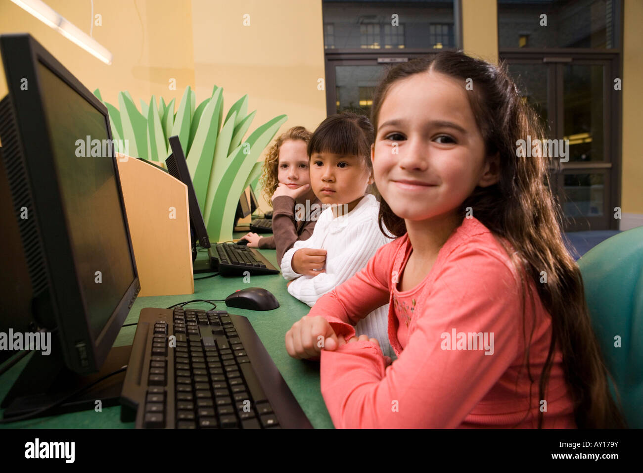 Portrait of schoolgirls sitting by computer in the library Stock Photo ...