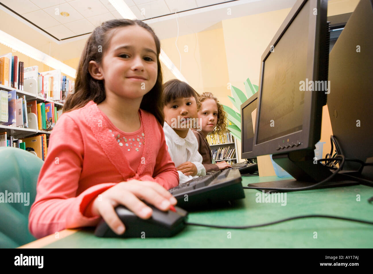 Portrait of schoolgirls using computer in the library Stock Photo - Alamy