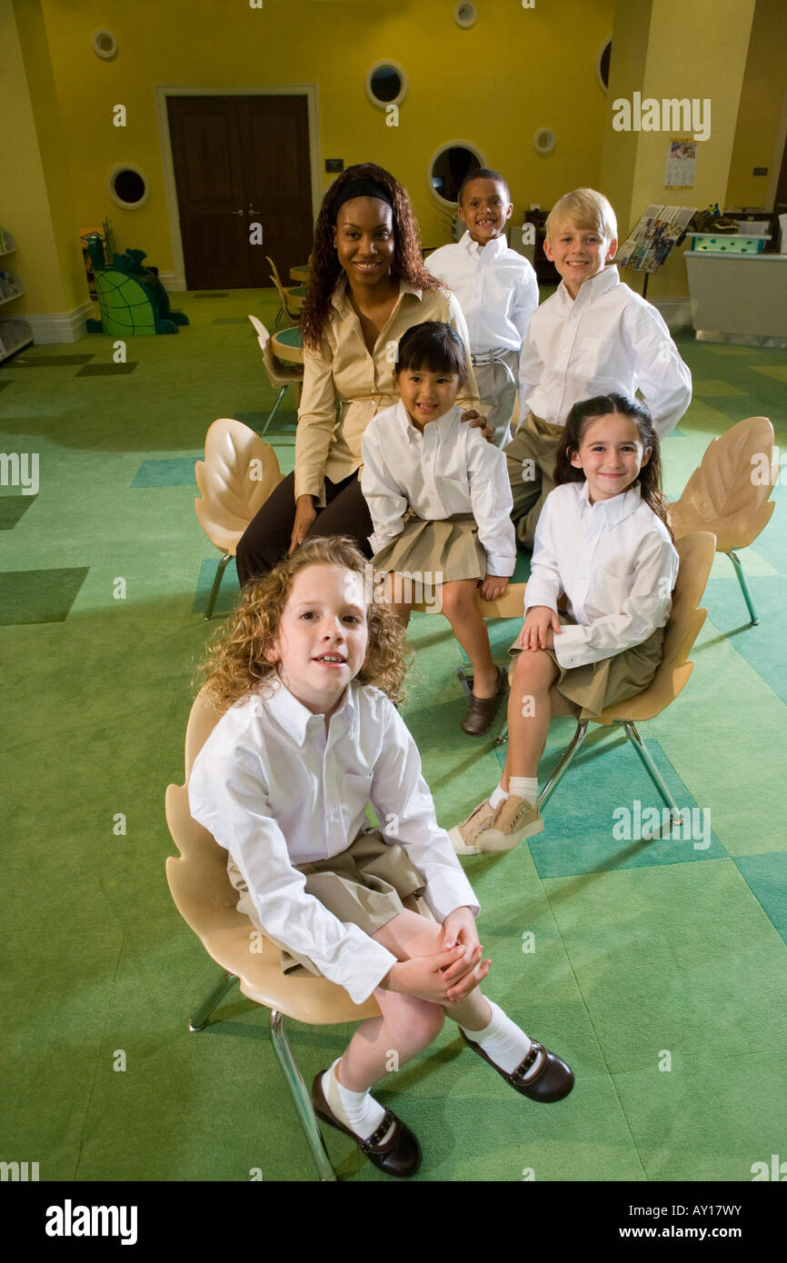 Portrait of a teacher sitting with students in the library Stock Photo ...