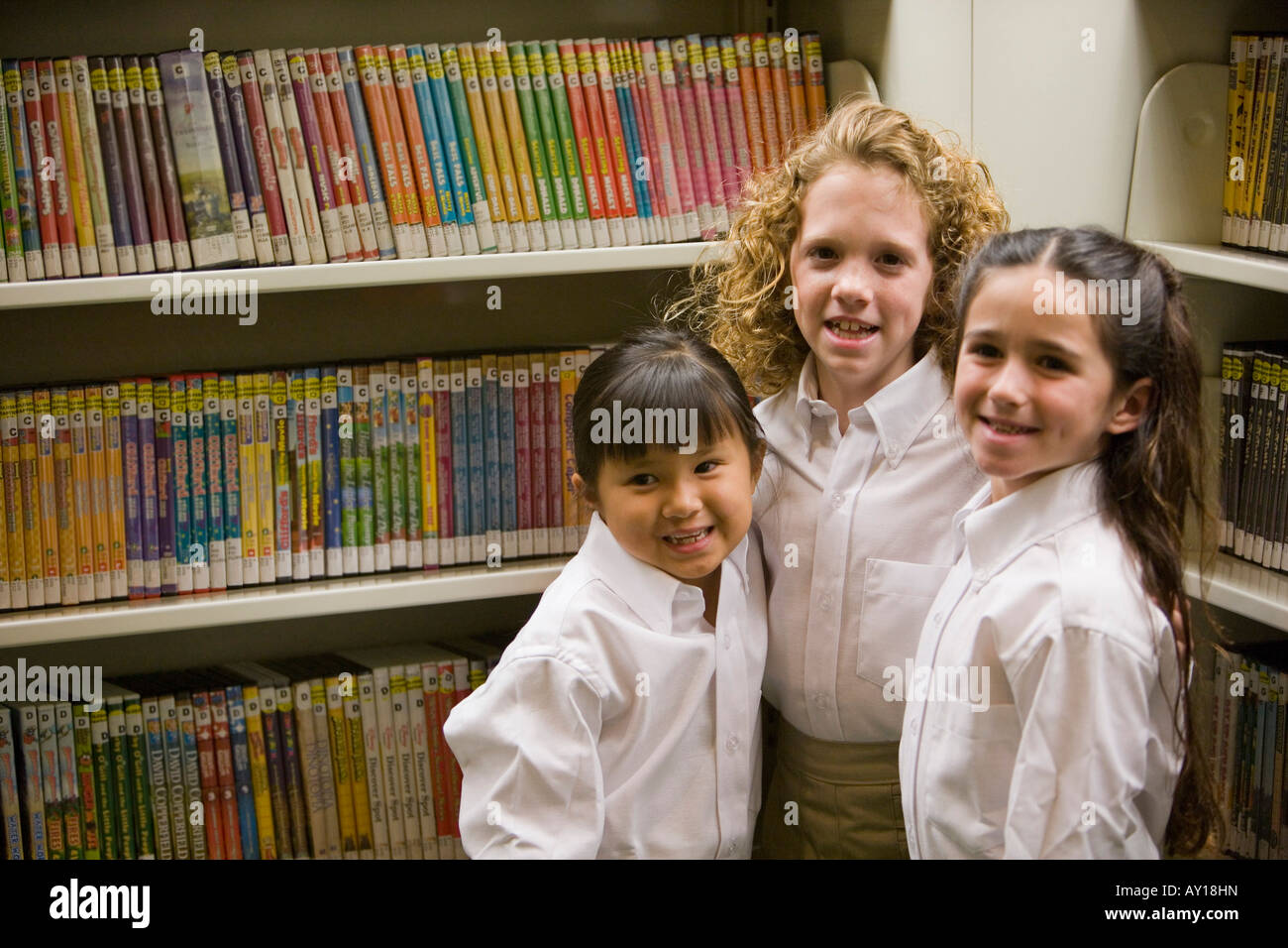 Portrait of smiling schoolgirls standing by shelf in the library Stock ...