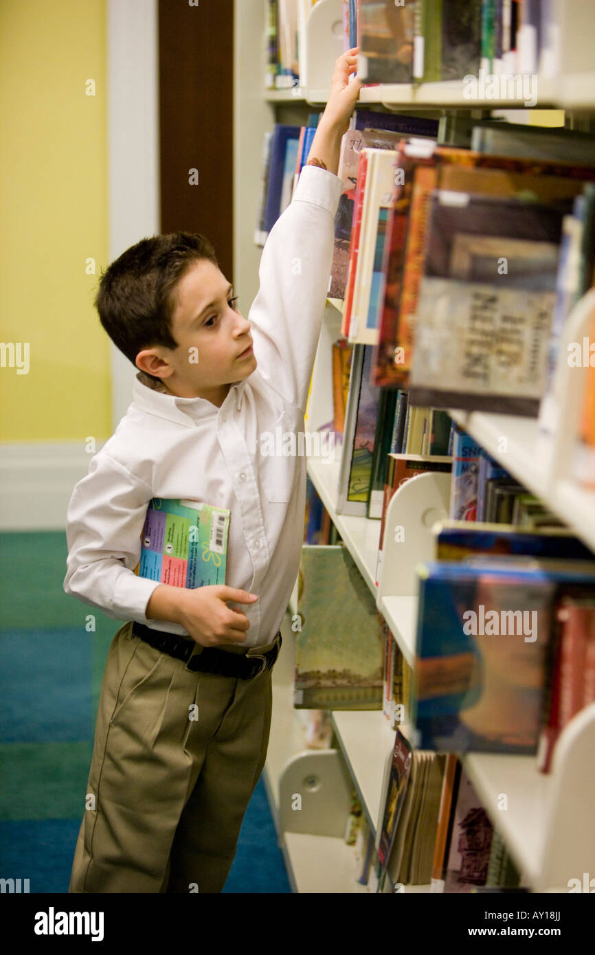 Schoolboy removing a book from shelf in the library Stock Photo - Alamy