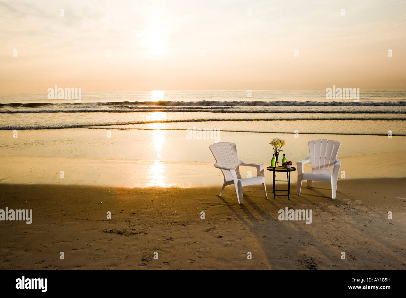 Table with chairs arranged on the beach with sunset in background Stock ...