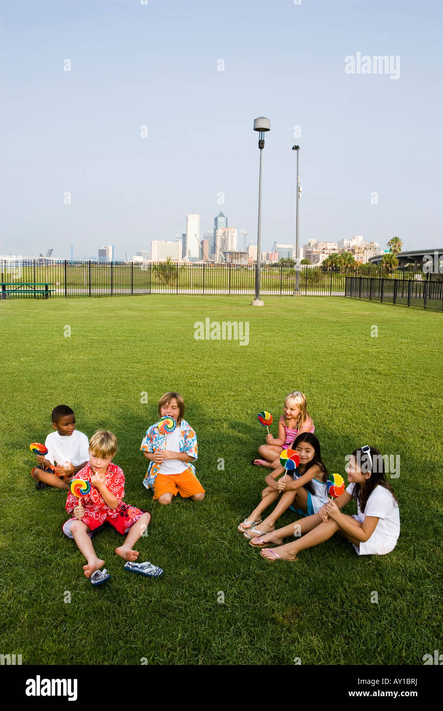 Children sitting on grass and eating lollipops Stock Photo - Alamy